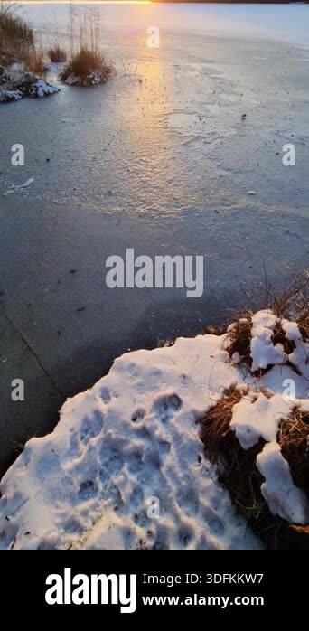 Beautiful golden hour sunset reflecting on the surface of a frozen lake ...