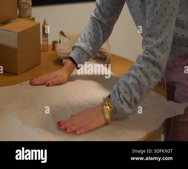 High-angle view of hands wrapping a piece of clothing in patterned ...