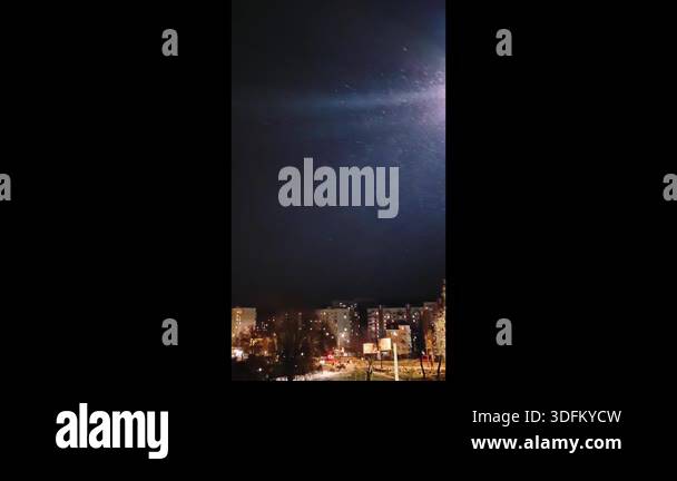 Nighttime urban scene with snow falling through a bright streetlight ...