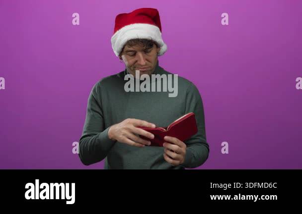 Hispanic man wearing a christmas hat inspects an empty wallet against a ...