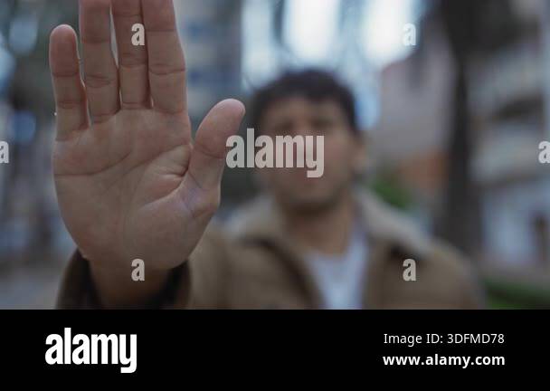 Hispanic man gesturing stop outdoors on a street capturing the urban ...