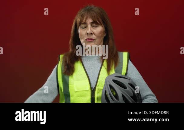 Woman expressing surprise while wearing a yellow vest and holding a ...