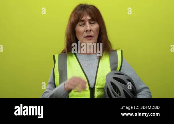 Hispanic senior woman in a yellow vest holding her neck in pain against ...