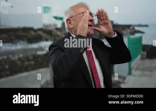 Senior man in business suit shouting at seaside, with ocean background ...