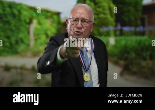 Senior man in a suit wearing a medal points angrily during a business ...