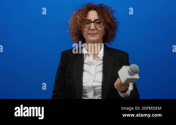 Brunette hispanic woman in a suit gestures with microphone excitedly ...