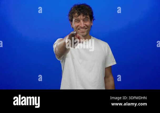 Smiling hispanic man in white shirt against blue background making ...