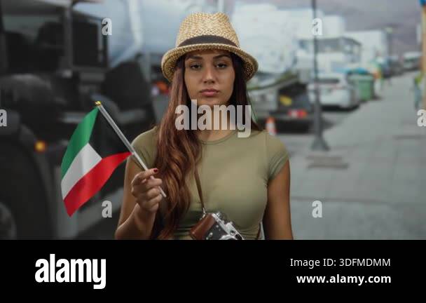 Hispanic woman holding kuwait flag in outdoor street setting captures ...