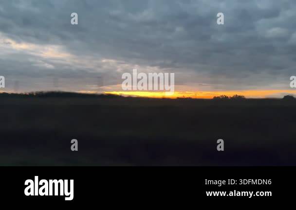 Dark tree silhouettes contrast with glowing orange horizon, creating a ...