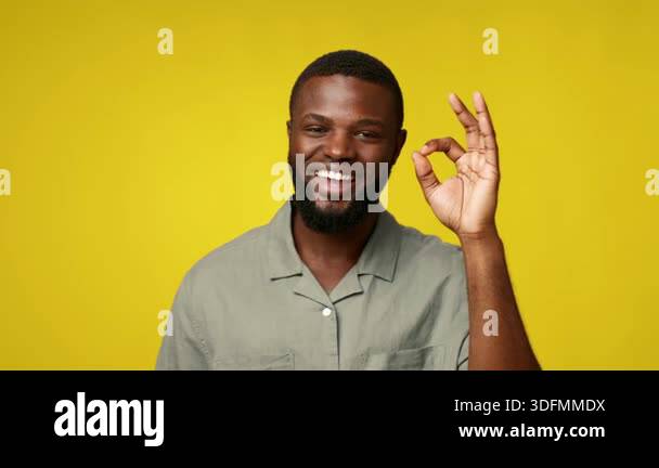 A cheerful African American millennial man stands alone against a ...