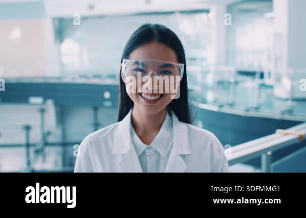A smiling Asian woman in a lab coat and safety goggles stands ...