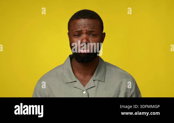 An African American man stands isolated with a sad expression. He wears ...