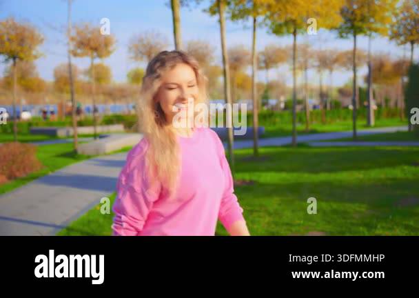 Portrait blond hair happy woman walking on city street public park ...