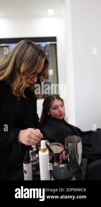 Professional female hairstylist with glasses mixing hair coloring ...