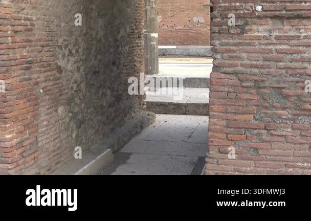 Tourist walking through an ancient Roman archway in Pompeii, framed by ...