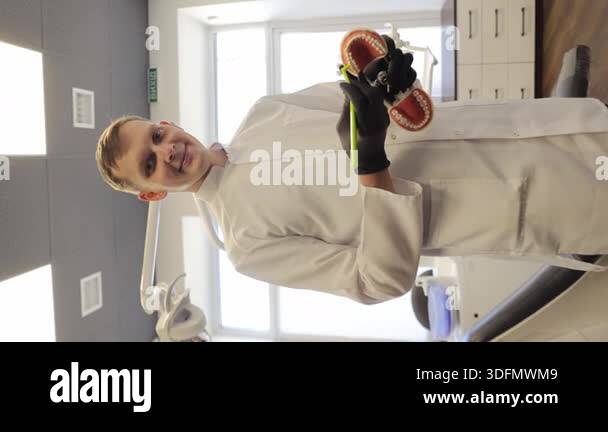 Young male dentist explaining proper tooth brushing technique on a ...