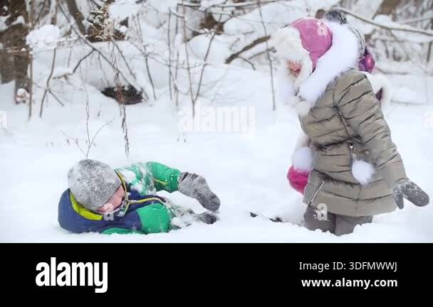 Winter forest. Smiling children in bright clothes playing with snow ...