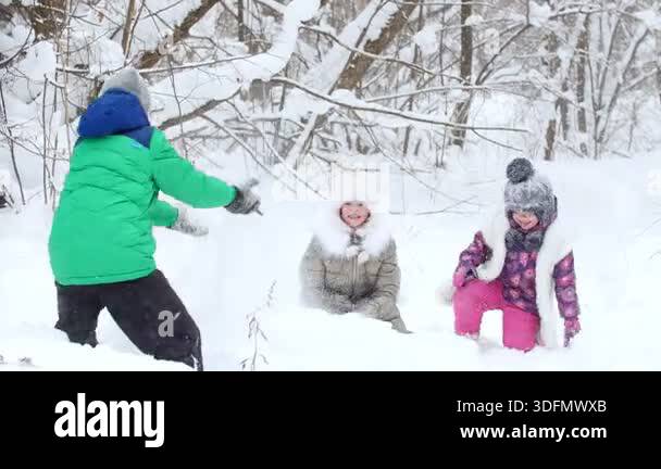 Winter forest. Children in bright clothes playing in snow. Mid shot ...