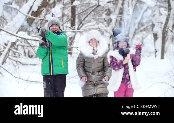 Winter forest. Cheerful children in bright clothes blow up christmas ...