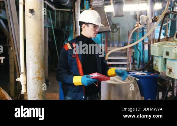 A man engineer walking in manufacturing plant and pushing buttons. Mid ...