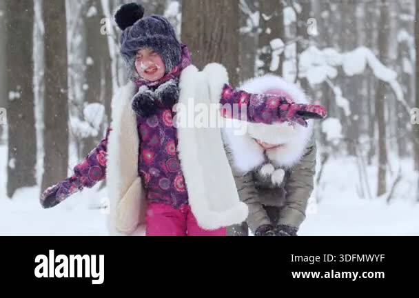 Two little girls playing with snow on the in winter forest. Snow on ...