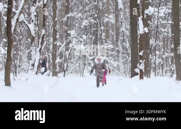 Two little girls running after each other in winter forest. Mid shot ...