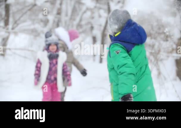 Winter forest. A little boy throwing snow in his sisters. Mid shot ...