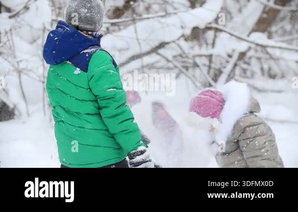 Winter forest. Children in bright clothes playing with snow. Mid shot ...