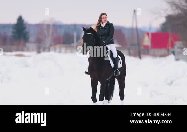 A woman with long hair riding a horse in a village in winter time. Mid ...
