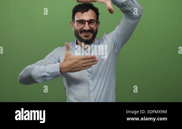 Hispanic man with beard and glasses in blue shirt framing face against ...