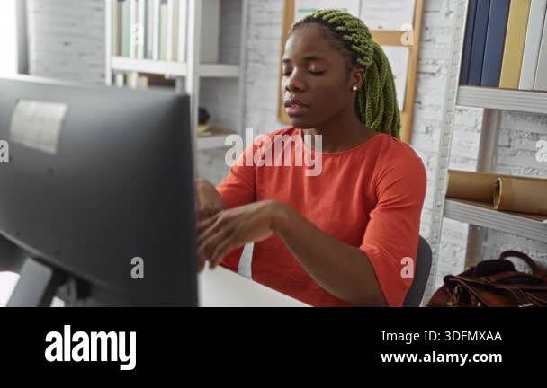 Woman in office stressed at computer with braided hairstyle looking ...