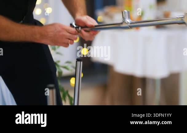 Close-up of workers hands using a hex key to assemble a shiny metal ...