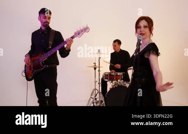 A musical band in black clothes playing song in the bright studio ...