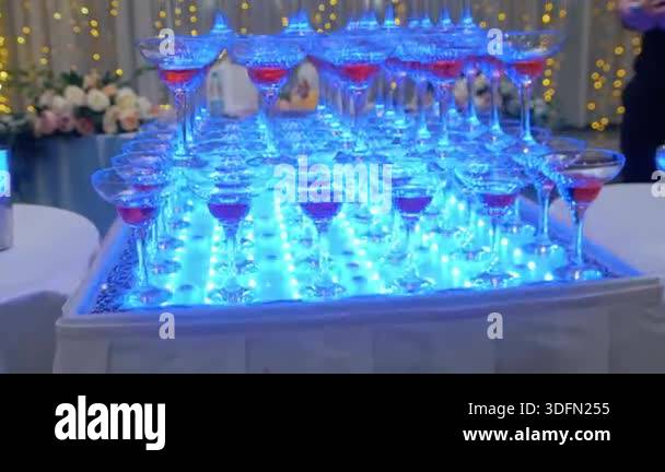 Glowing pyramid of champagne glasses with colorful illumination at a ...