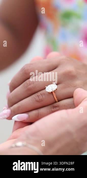 A man gently places a beautiful oval diamond engagement ring on his ...