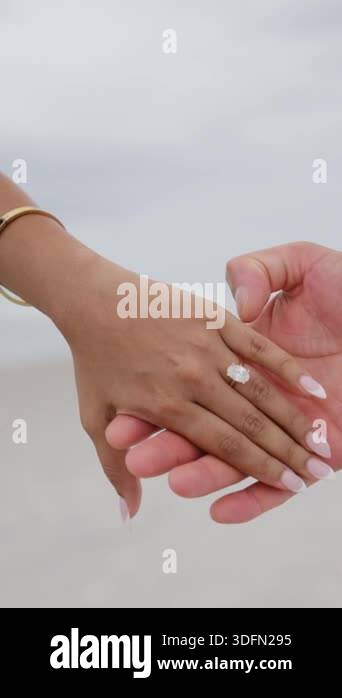 Newly engaged couple holding hands on a beach, showing a beautiful ...