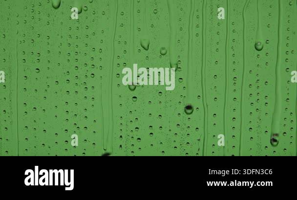 Close up of wet glass with dripping water drops and streaks of rain, on ...