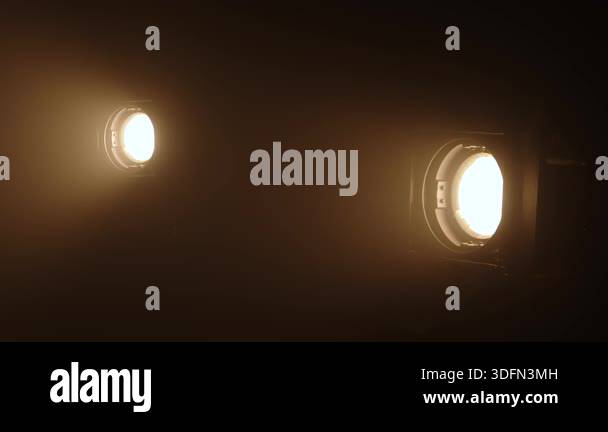 Two powerful studio spotlights cast warm beams of light into the ...