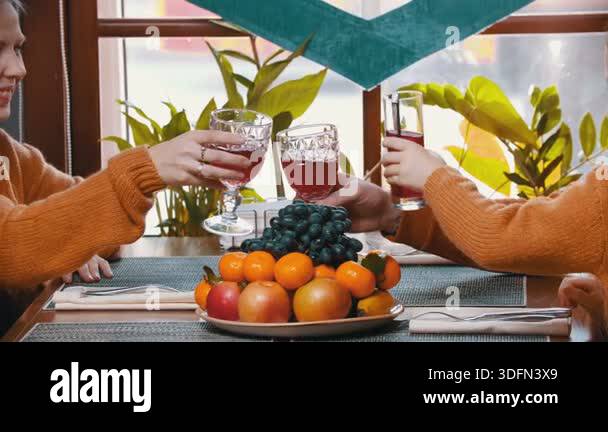 A family sitting in the restaurant clinking glasses of juice. Mid shot ...