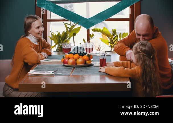 A happy family sitting in the hotel restaurant and talking to each ...