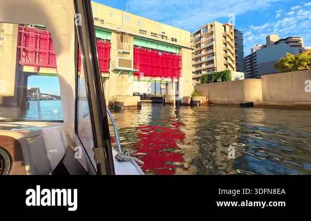 Small boat moving at sea near Tokyo Odaiba, showing reclaimed land ...