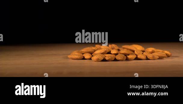 Super slow-motion of almonds fall on wooden table. Healthy snack ...