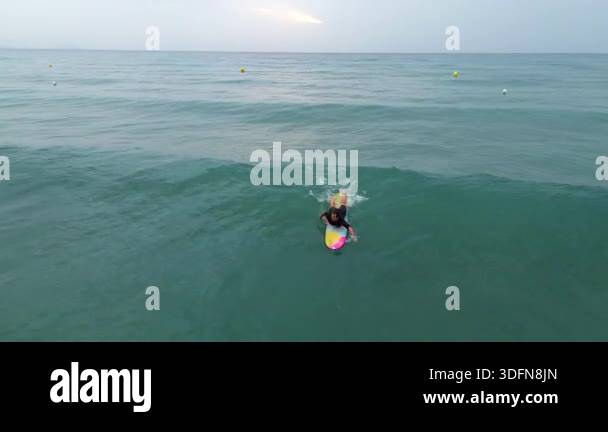Aerial drone footage of a surfer riding small waves in the ...