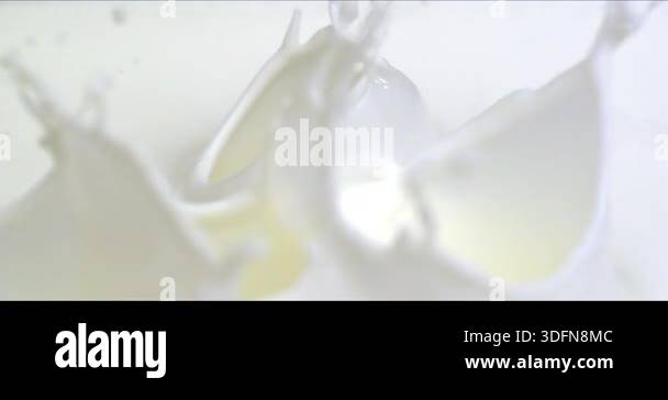 Slow motion almonds falling into milk. Milky splash. Commercial shot ...