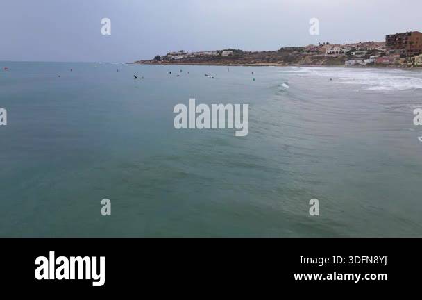 People in wetsuits learning to catch a wave on a surfboard, Spain ...