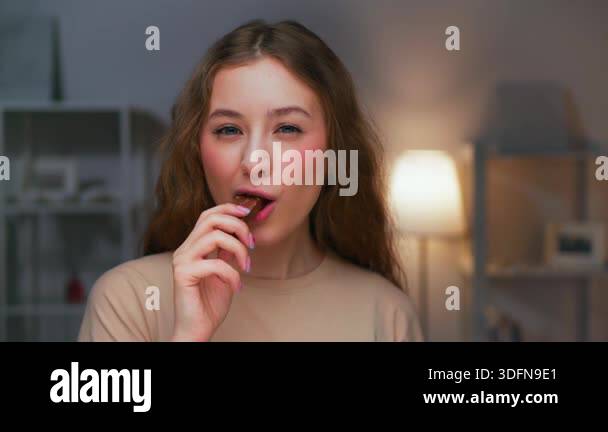 Portrait of Young Woman Eating Sweet Food and Looking at Camera Close ...