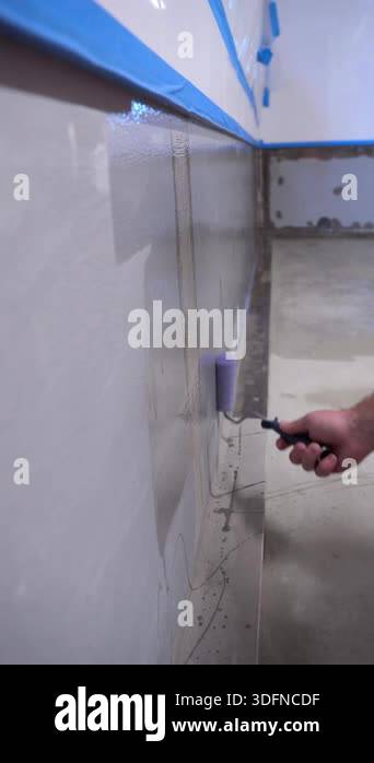 Close up of roller spreading wet coating on wall, construction and ...