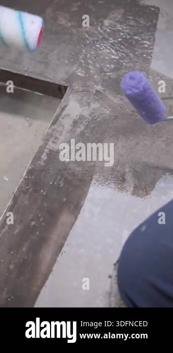 Close up of epoxy floor coating being rolled onto concrete surface ...