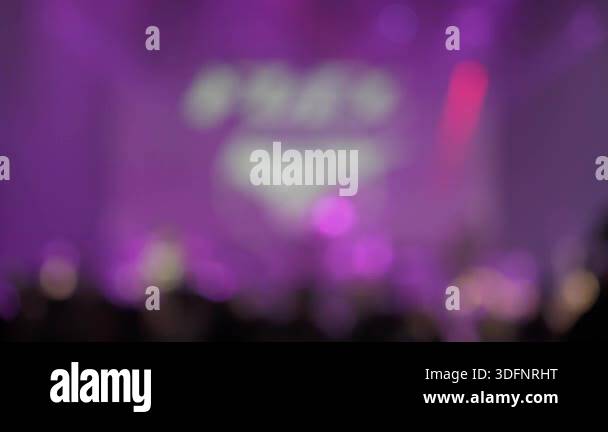 Blurred concert stage in purple light with a bright projection screen ...