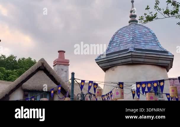 A whimsical tower roof and pastel shingles rise above strings of ...